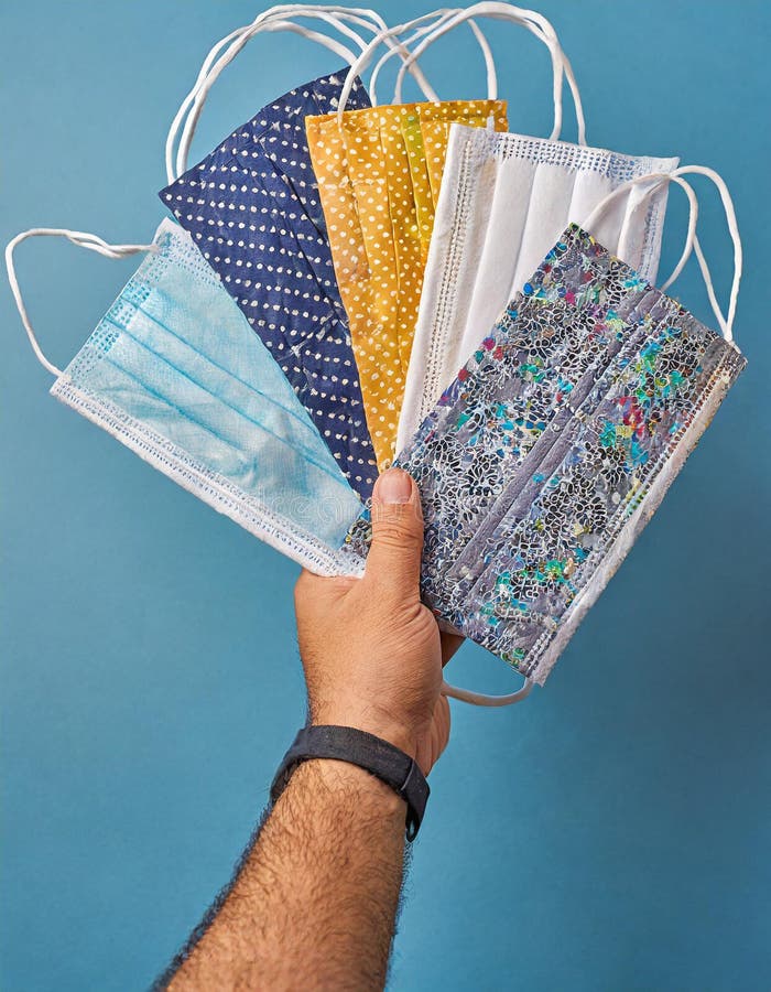A Hand Holding Several Face Masks of Different Shapes and Colors Stock ...