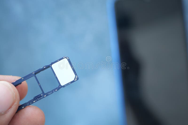 Hand Holding SIM Card Tray with Smartphone in Background Stock Photo ...