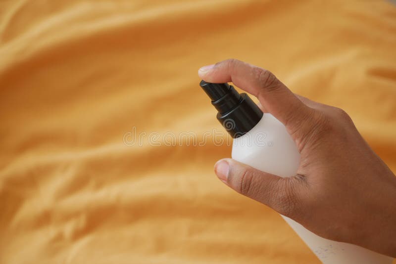 Hand Holding a Spray Bottle Above a Yellow Fabric Surface Stock Photo ...