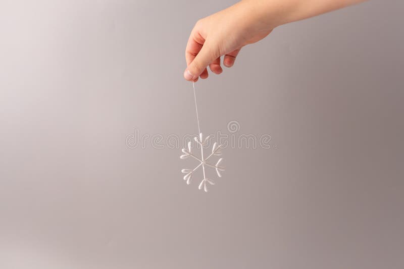 A Hand Holding a String from Which a Snowflake-shaped Ornament is ...