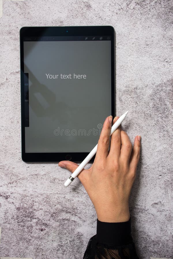 Hand Holding a Stylus Next To a Tablet on a Stone Textured Surface ...