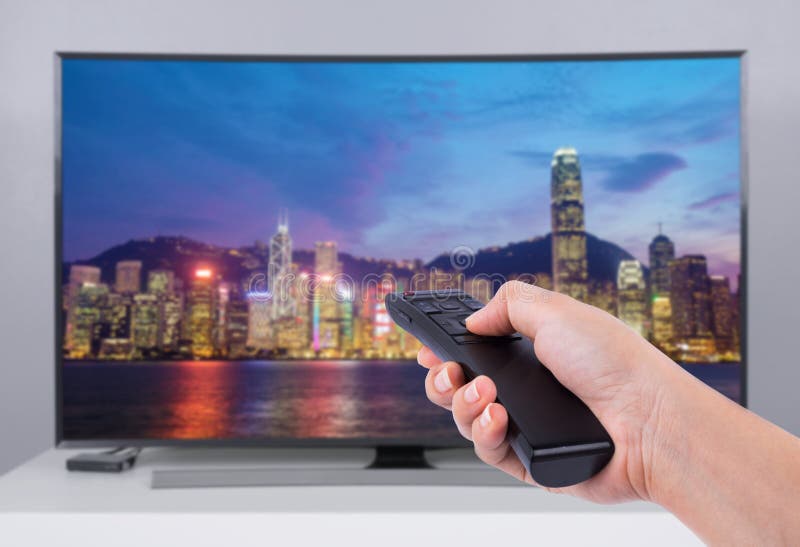 Hand Holding TV Remote Control with a Television and City Screen Stock ...