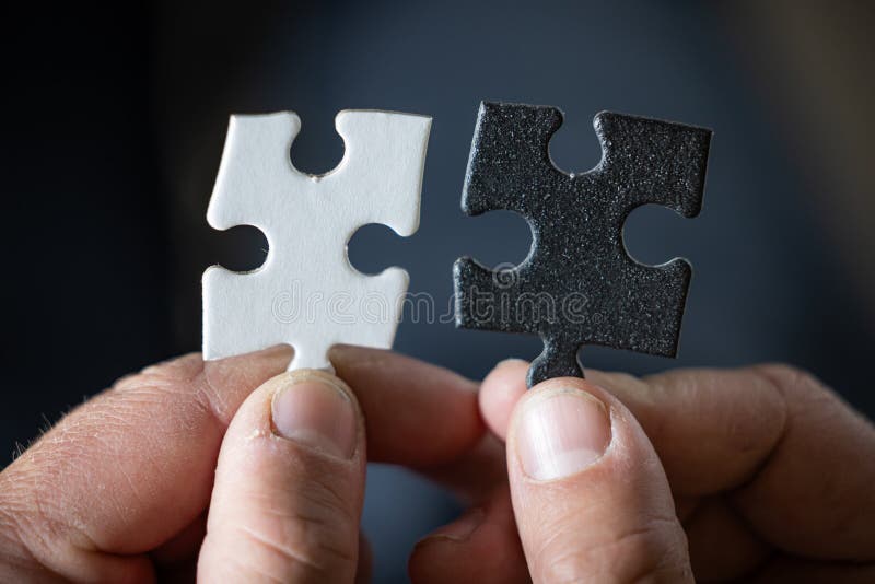 A Hand Holding Two Puzzle Pieces, One White and One Black Stock Image ...