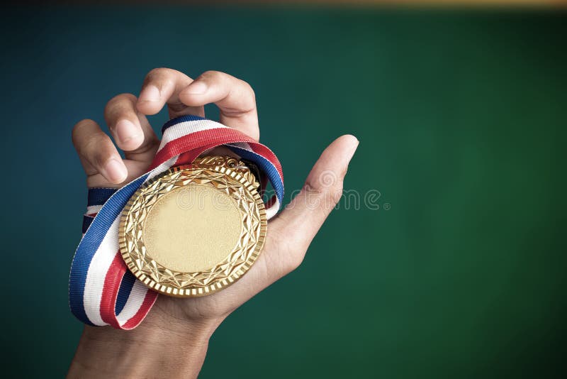 Hand Holding Up a Gold Medal Stock Photo - Image of gold, award: 63033994