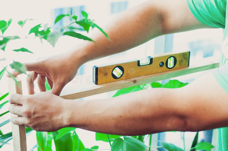 Hand Holding Water Level and Checking the Adjustment To a Wooden Plank ...
