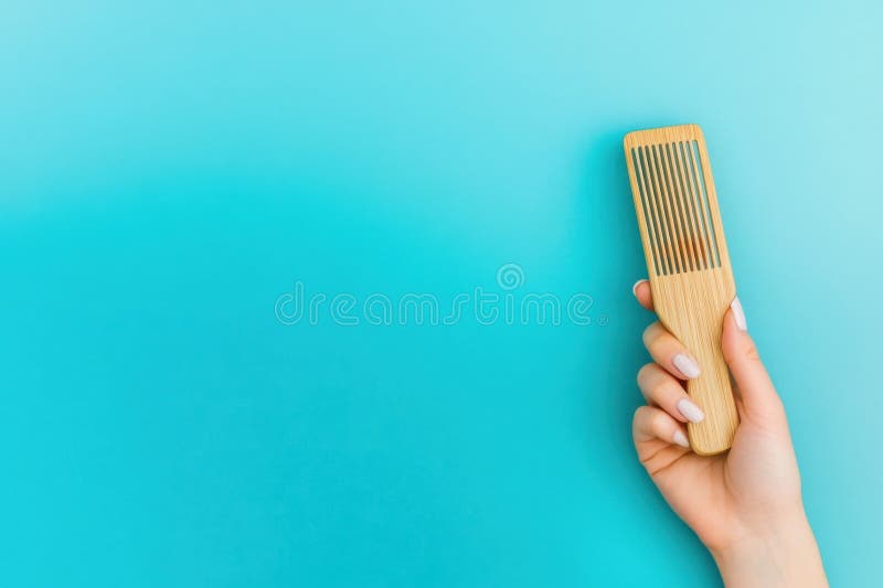 Hand Holding Wooden Comb on Blue Background Stock Photo - Image of ...
