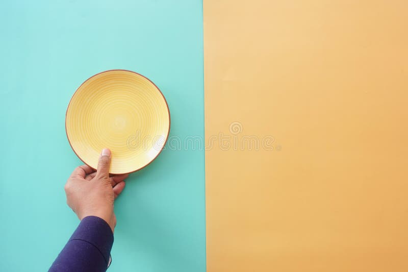 Hand Holding Yellow Plate on Split Color Background Stock Photo - Image ...