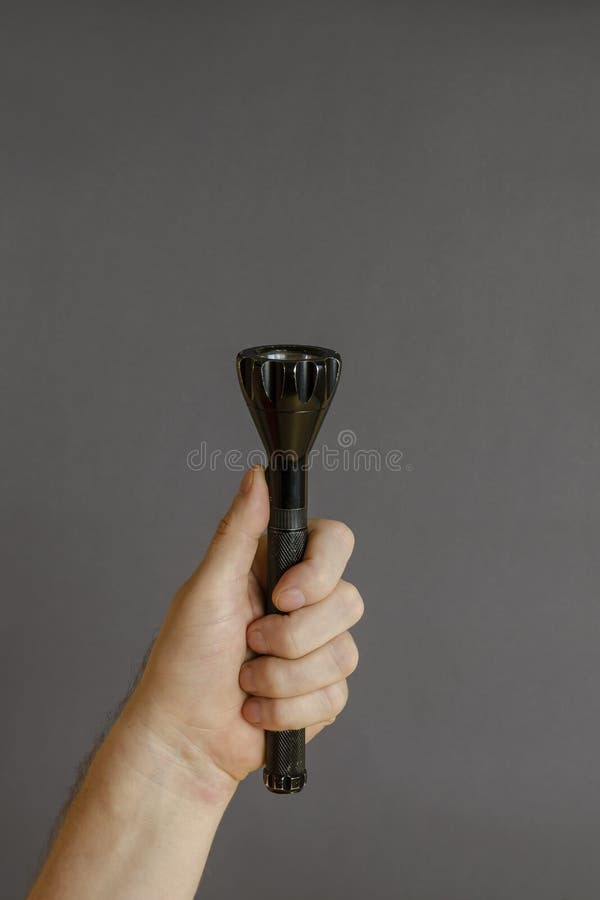 A Hand Holds a Black Modern LED Flashlight on a Gray Background Stock ...