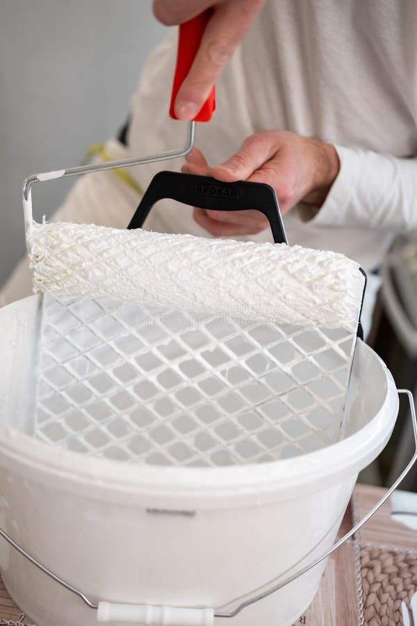 Person Applying Paint Using a Roller in a White Bucket during a Home ...