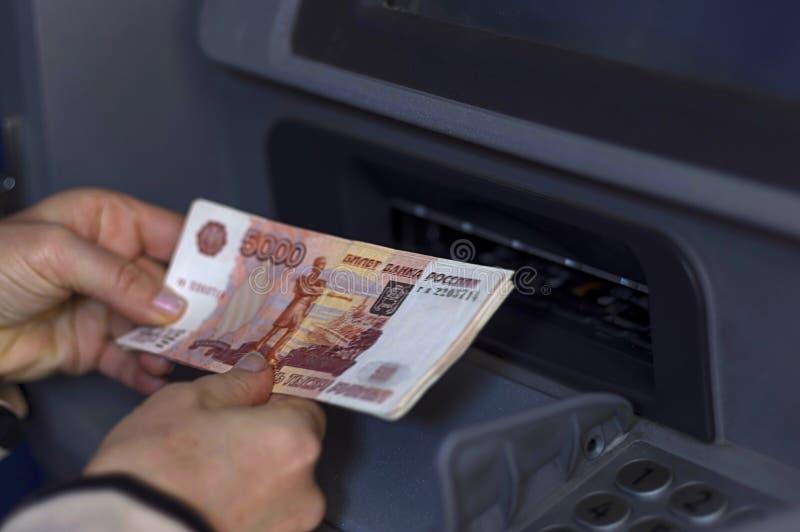 The Hand Holds a Stack of Money in Front of the Open ATM Receive Stock ...