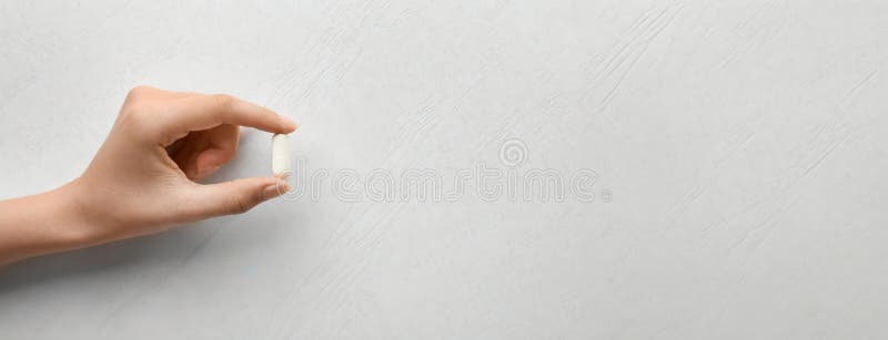 A Hand Holds a Tiny White Pill between Thumb and Forefinger on a ...