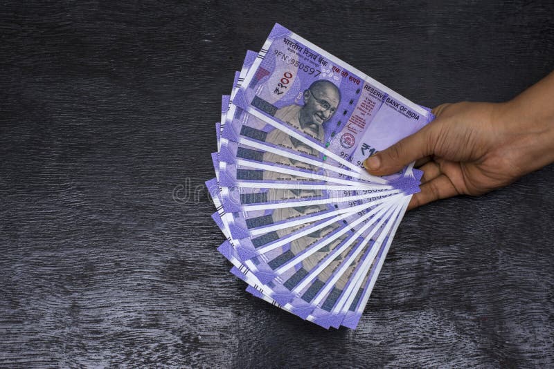 A Hand Holing Spread of Indian Currency Notes of 100 Rupees in a Dark ...