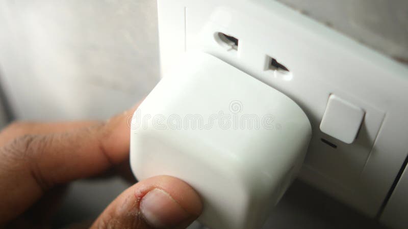 A Person Connecting a Charger into an Electrical Wall Socket for Use ...