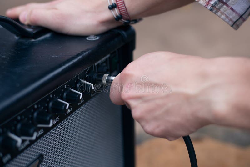 Hand Inserts a Cord Jack into a Combo Amplifier for Electric Guitar ...