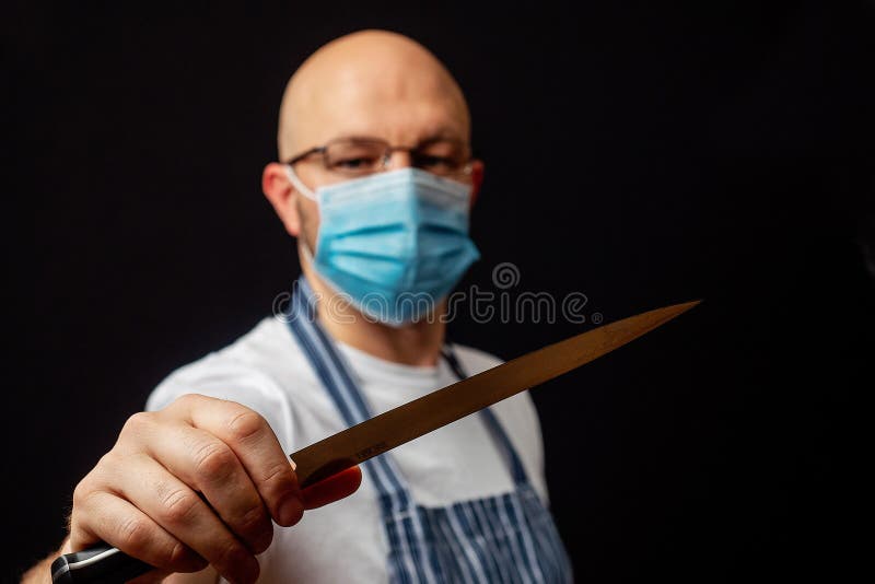 Hand and Knife in Focus, Bald Butcher Out of Focus on a Dark Background ...