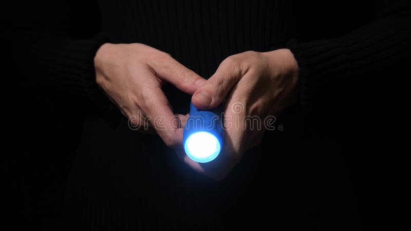 Hand with a Led Flashlight Shining in the Darkness with Blue Beam into ...