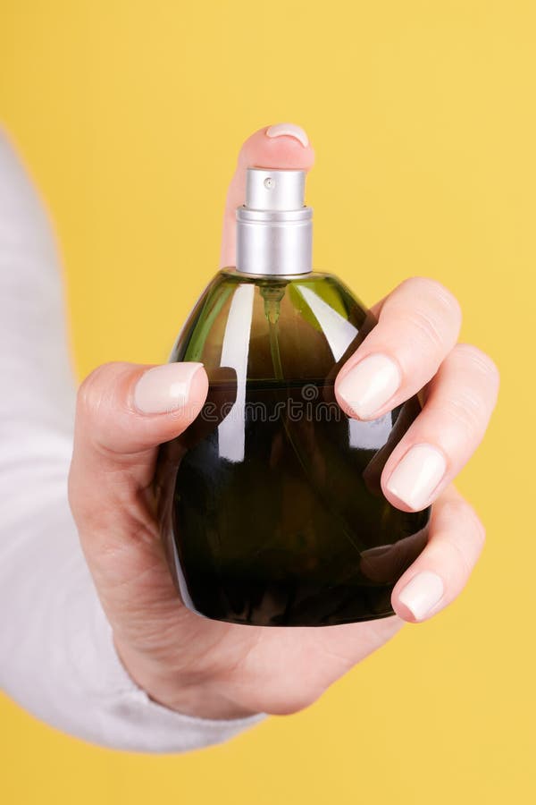 Hand with Luxury Perfume Bottle. Isolated on Yellow Background Stock ...