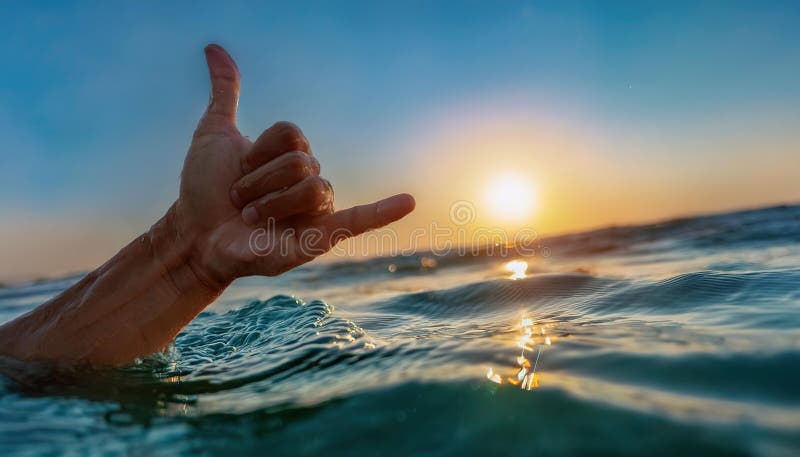 A Hand Making a Shaka Sign in the Ocean Water during a Sunset. Stock ...