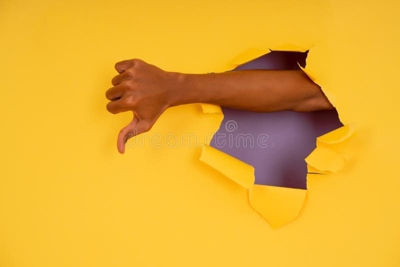 Hand Making Thumb Down Gesture with Hand through Torn Paper Wall. Stock ...