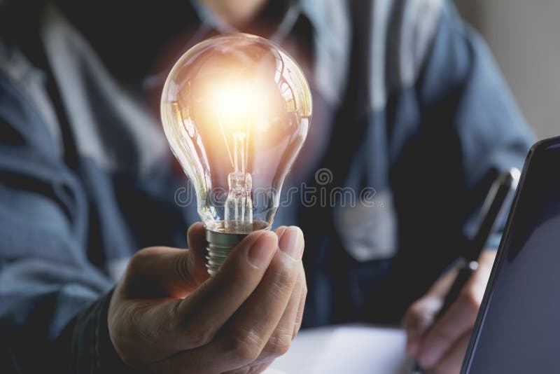 Hand of Male Holding a Light Bulb and Using a Laptop for Account Stock ...