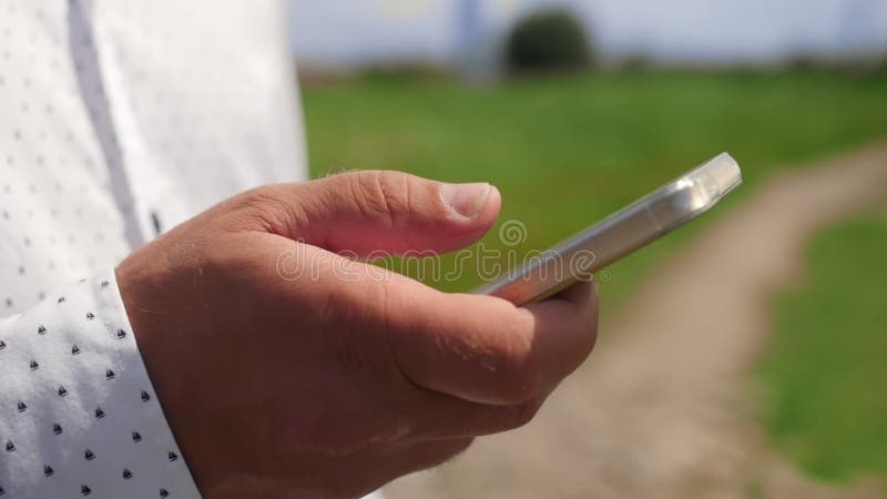 Hand of Man Using and Scrolling Phone in the Background of a Field ...