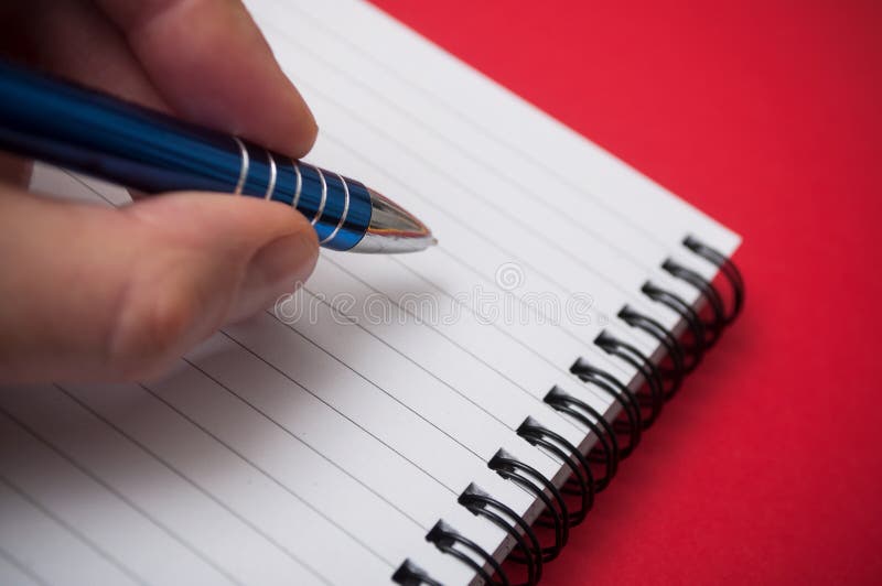 Hand of Man Writing with Blue Pen on Spirales Note Book on Red ...