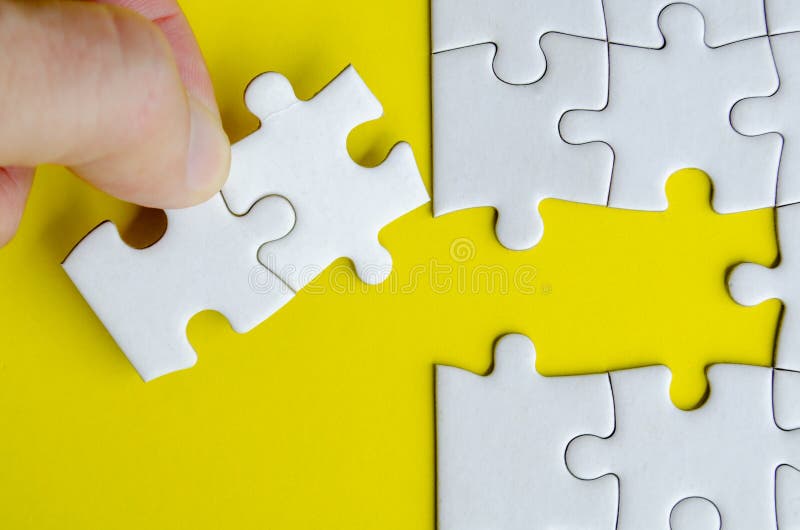 Hand Matching White Puzzle Pieces Lying on a Vibrant Yellow Surface ...