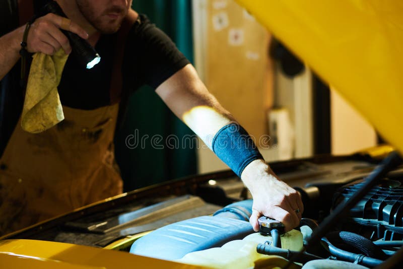 Hand of Mechanic Fixing Part of Car Engine while Directing Flashlight ...