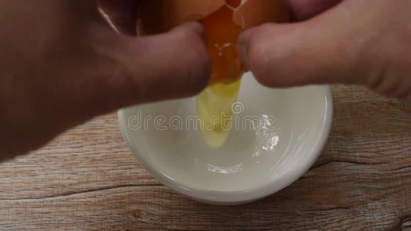 Hand Opened Shell and Raw Egg with Yolk Dropping in Cup on Table Stock ...