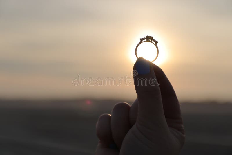 Hand of a Person Holding a Ring Against the Bright Light of the Sun ...