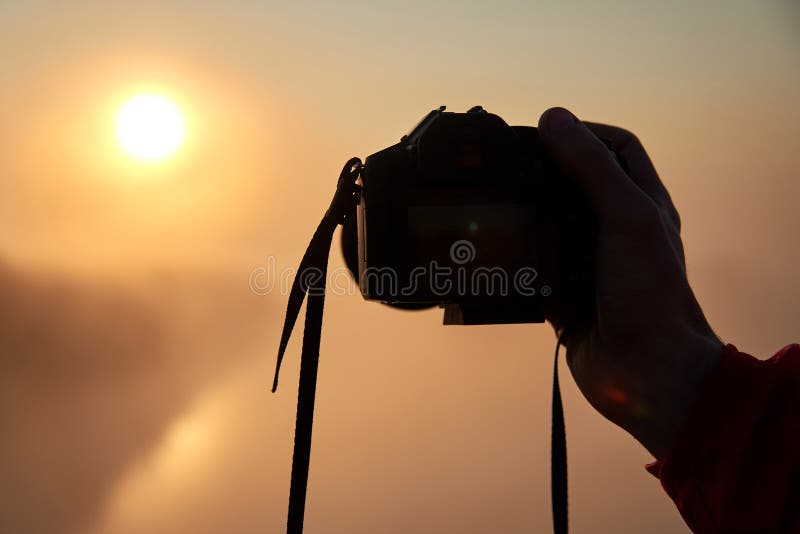 Hand of a Photographer with a Camera Over a River during a Sunrise ...