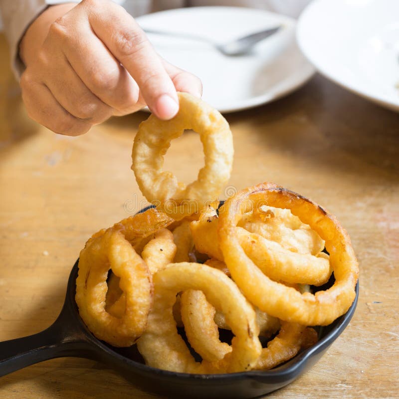 Hand Picking Onion Rings in Black Plate on the Wood Table in Restaurant ...