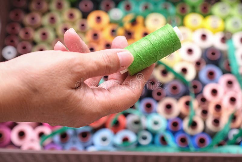 Hand Holding a Green Thread Over Blurry Colourful Background Stock ...