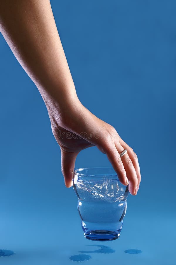 Hand Placing a Glass of Water on Blue Surface Stock Photo - Image of ...