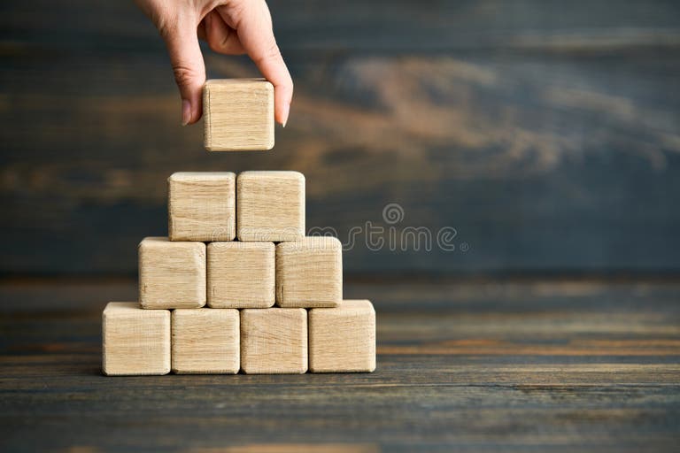 Hand Placing Last Wooden Cube on Pyramid Stack Stock Photo - Image of ...