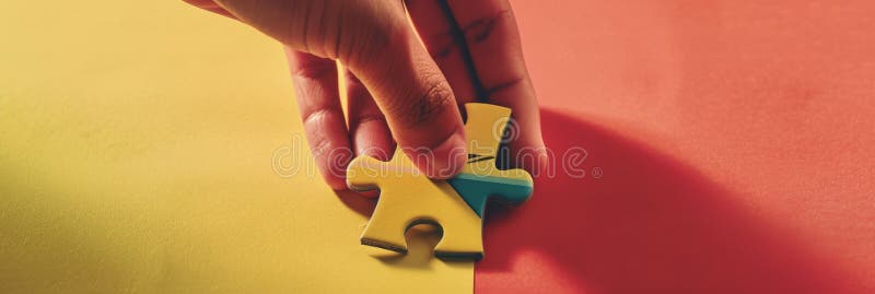 Hand Placing a Puzzle Piece on a Yellow and Red Background. Concept of ...