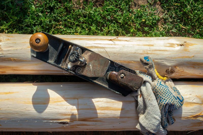 The Hand Plane and Gloves Lie on Damp Pine Logs Outside. Processing of ...