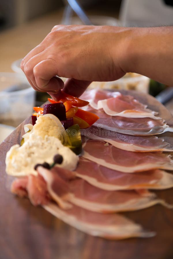 Hand Plating Appetizers on a Wooden Board with Proscuitto. Stock Image ...