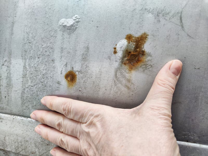 Hand Touching Noticeable Rust Stains on a Metallic Surface in a ...