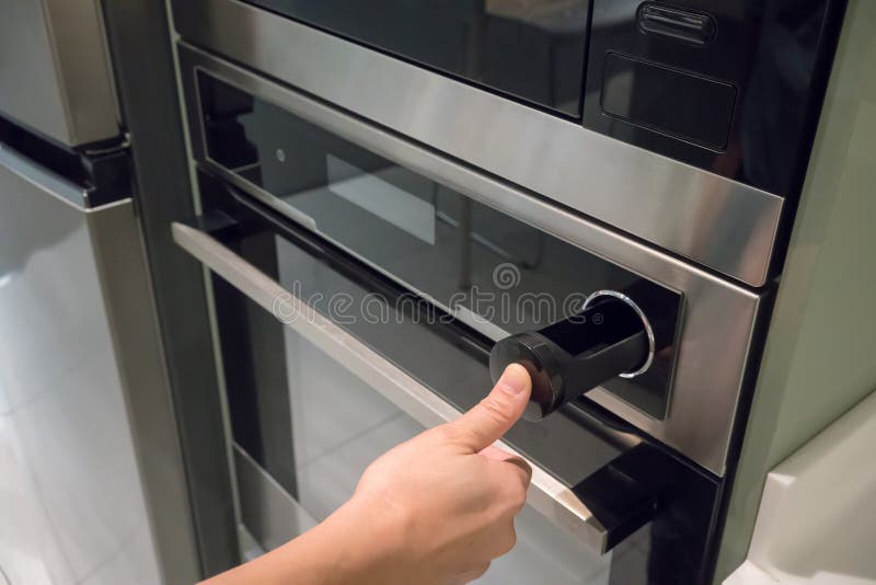 Hand Pressing Button on Silver Black Wall Oven with Built-in Mic Stock ...