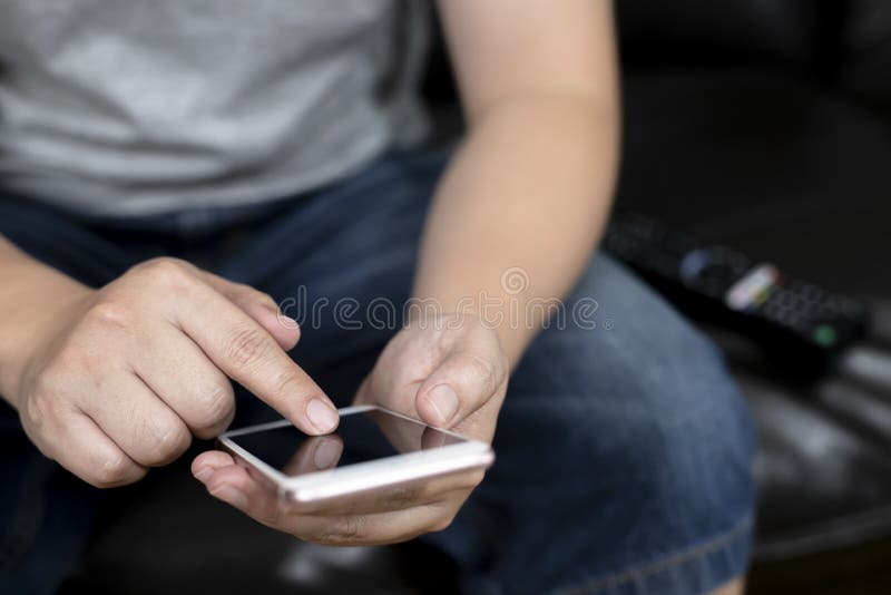 The Hand is Pressing the Phone and Remote Control To Select the Channel ...