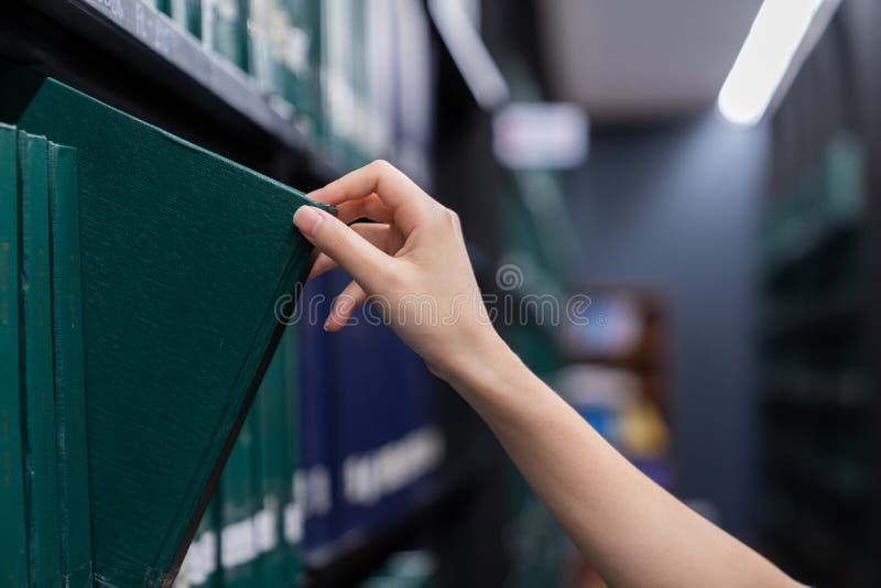 Hand Pulling a Thesis Book Off the Shelf in Library. Green Colors Books ...