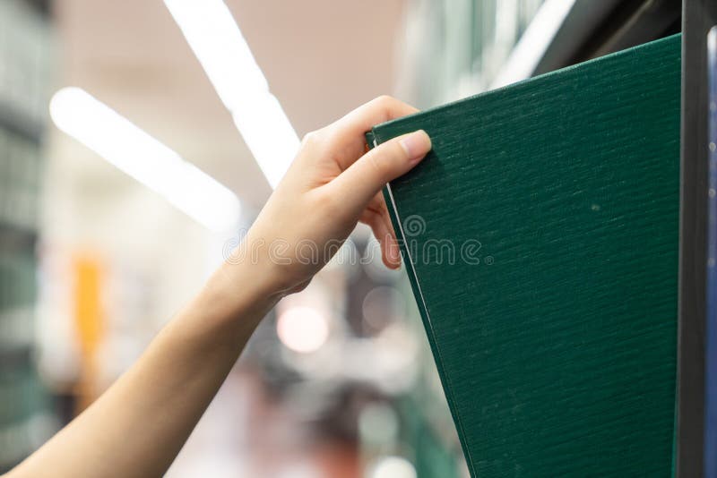 Hand Pulling a Thesis Book Off the Shelf in Library. Green Colors Books ...