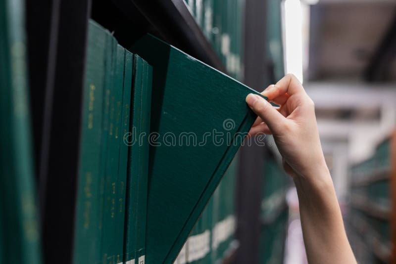 Hand Pulling a Thesis Book Off the Shelf in Library. Green Colors Books ...