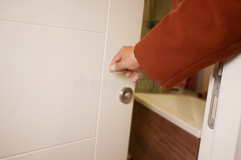 Hand Reaching for Door Handle in a Modern Bathroom Setting Stock Photo ...
