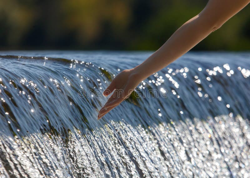 A Hand is Reaching into a Waterfall, Creating Ripples in the Water ...