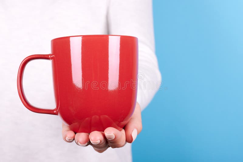 Hand with Red Mug with Handle. Isolated on Blue Background Stock Photo ...