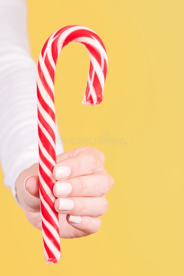 Hand with Red Striped Candy Cane. Isolated on Yellow Background Stock ...