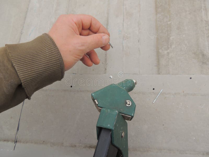 Hand with Riveter and Rivet on Gray Metal Sheet Background Stock Photo ...