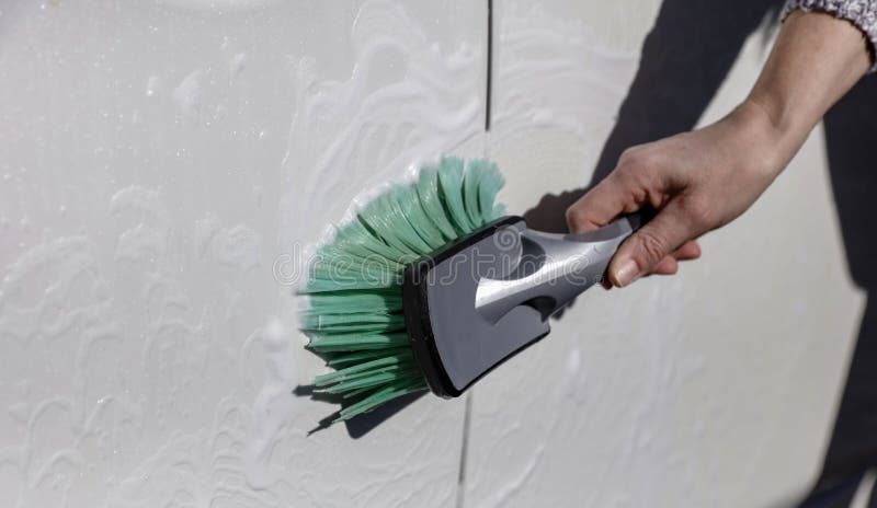 A Hand Washing the Side of a White Car Using a Brush and Soapy Water ...